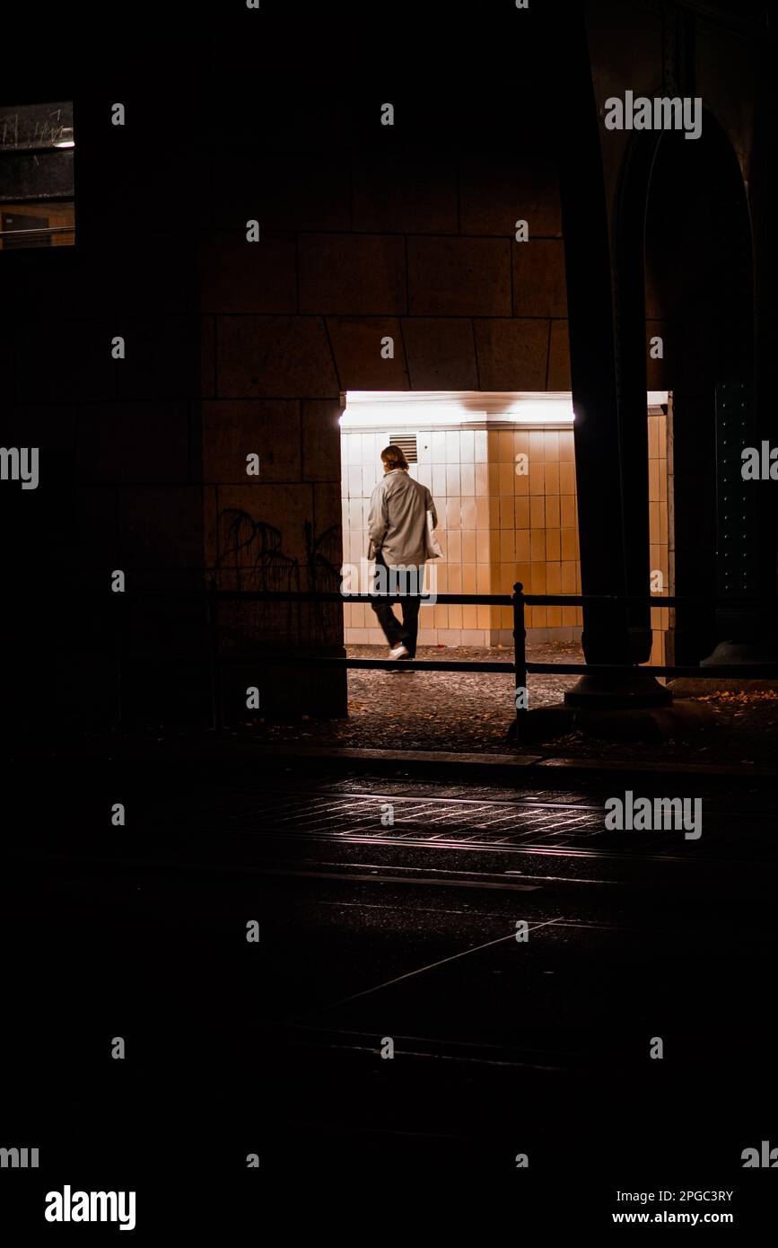 A man dressed in a grey shirt and dark trousers stands in the doorway ...