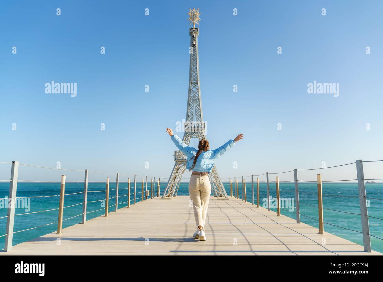 Large model of the Eiffel Tower on the beach. A woman walks along the ...