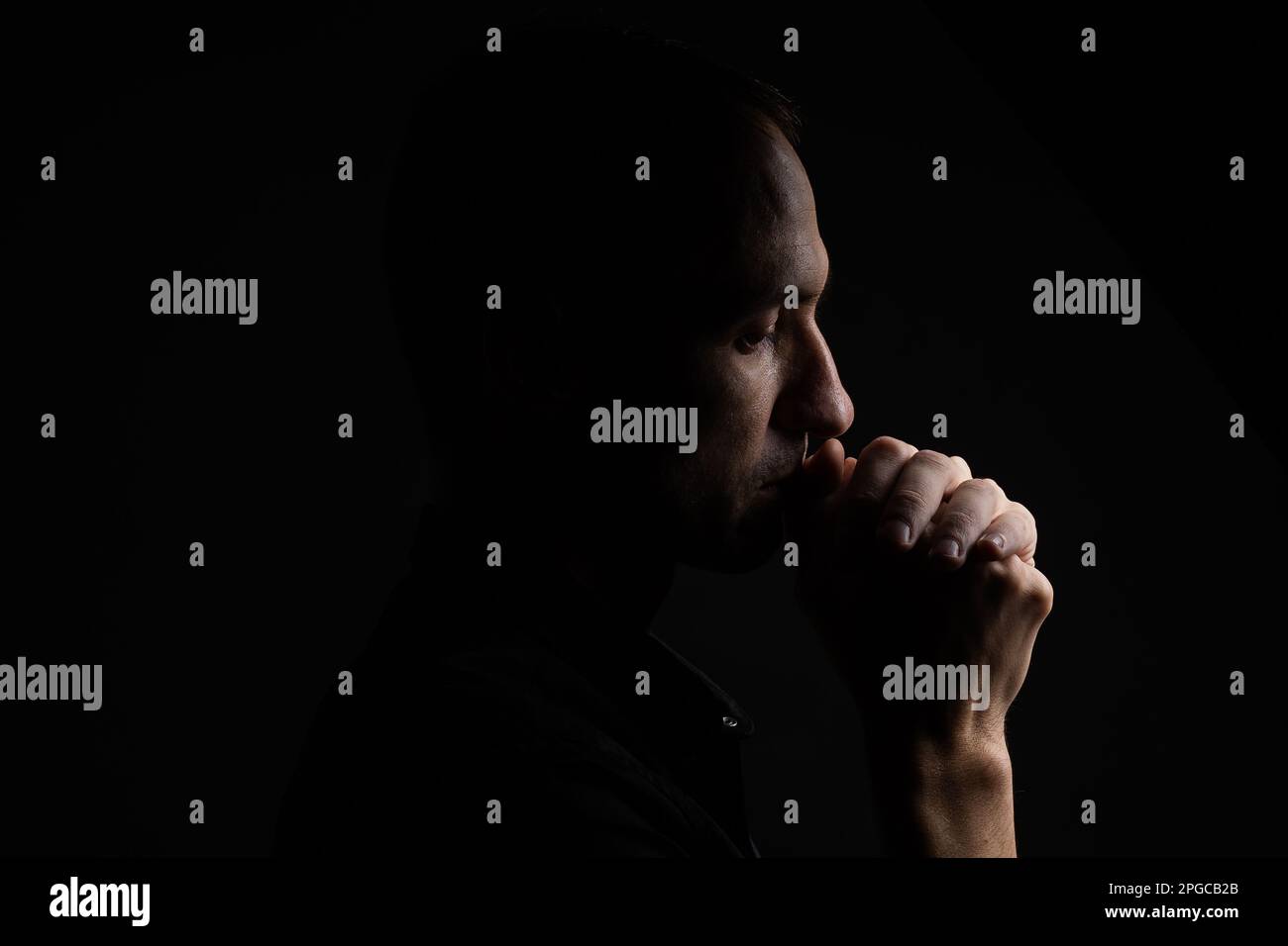 Close up of faithful mature man praying, hands folded in worship to god ...