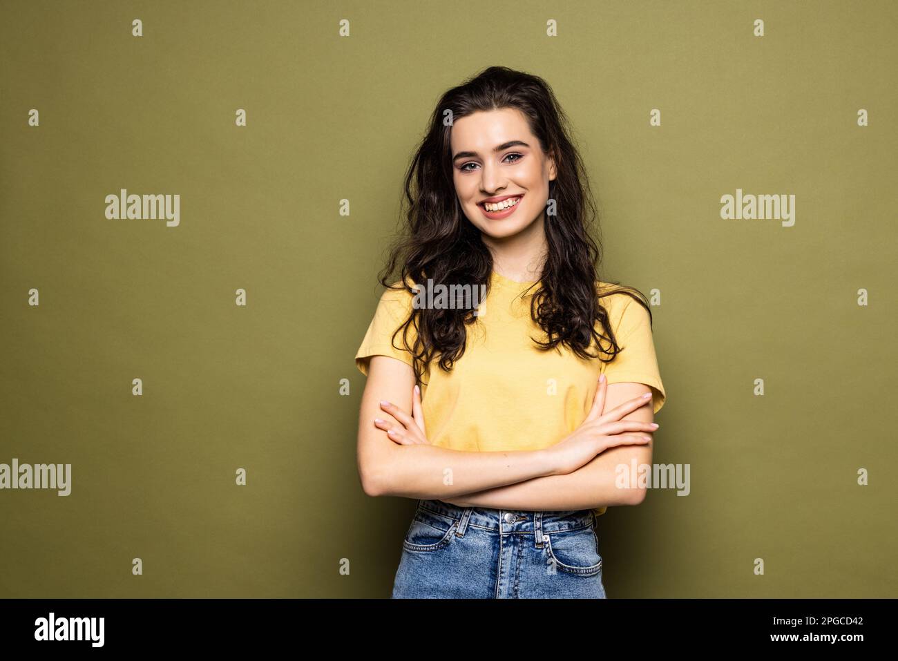 Young smiling attractive girl is posing in close pose with arms ...