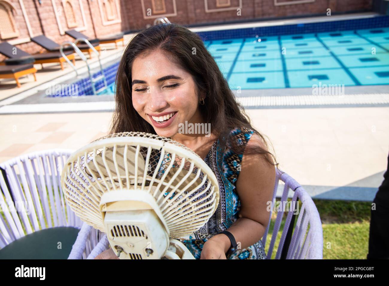 Young indian Woman enjoying air flow from electric fan and cooling her ...