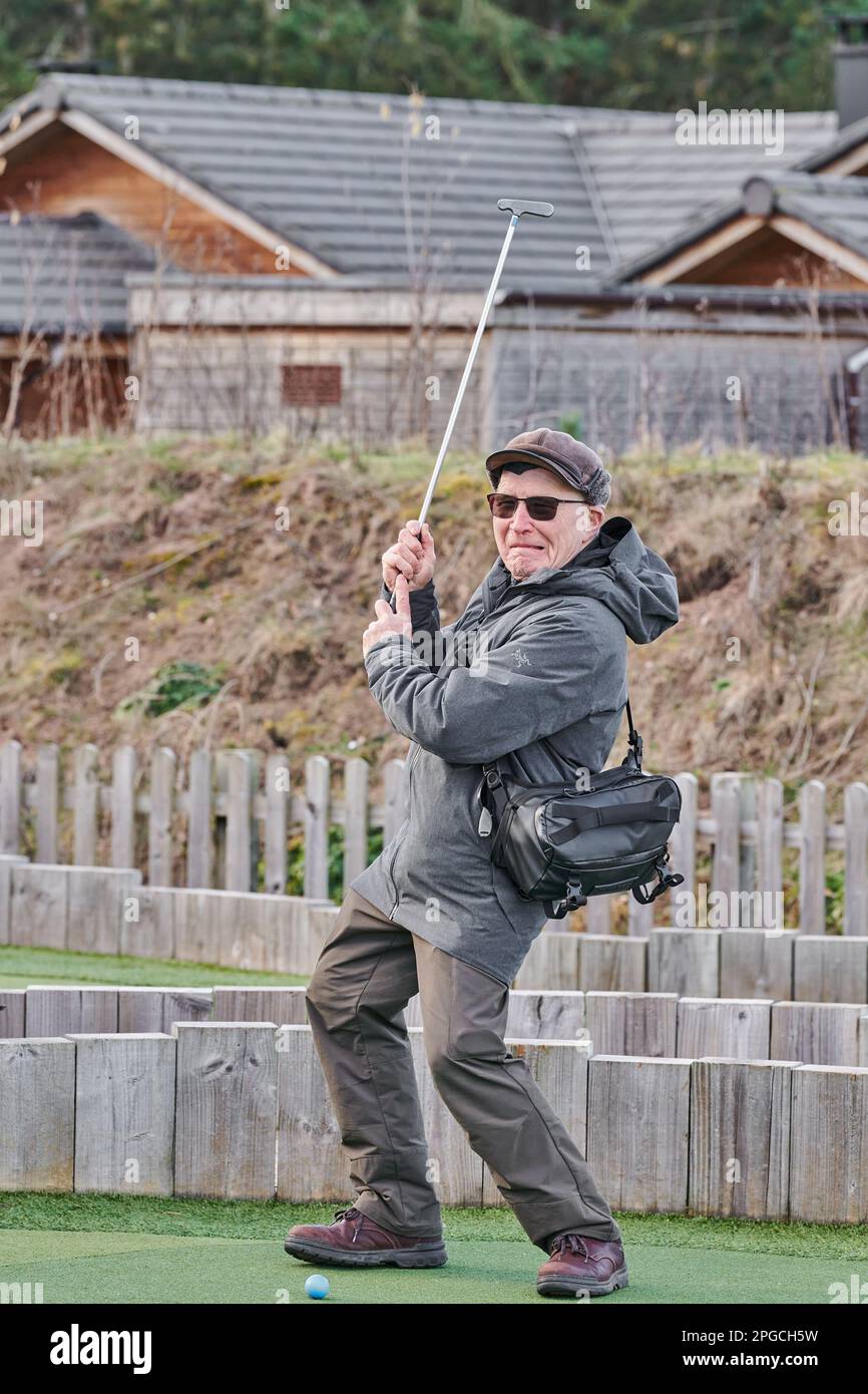 An attention seeking senior citizen with a golf club poses for the ...
