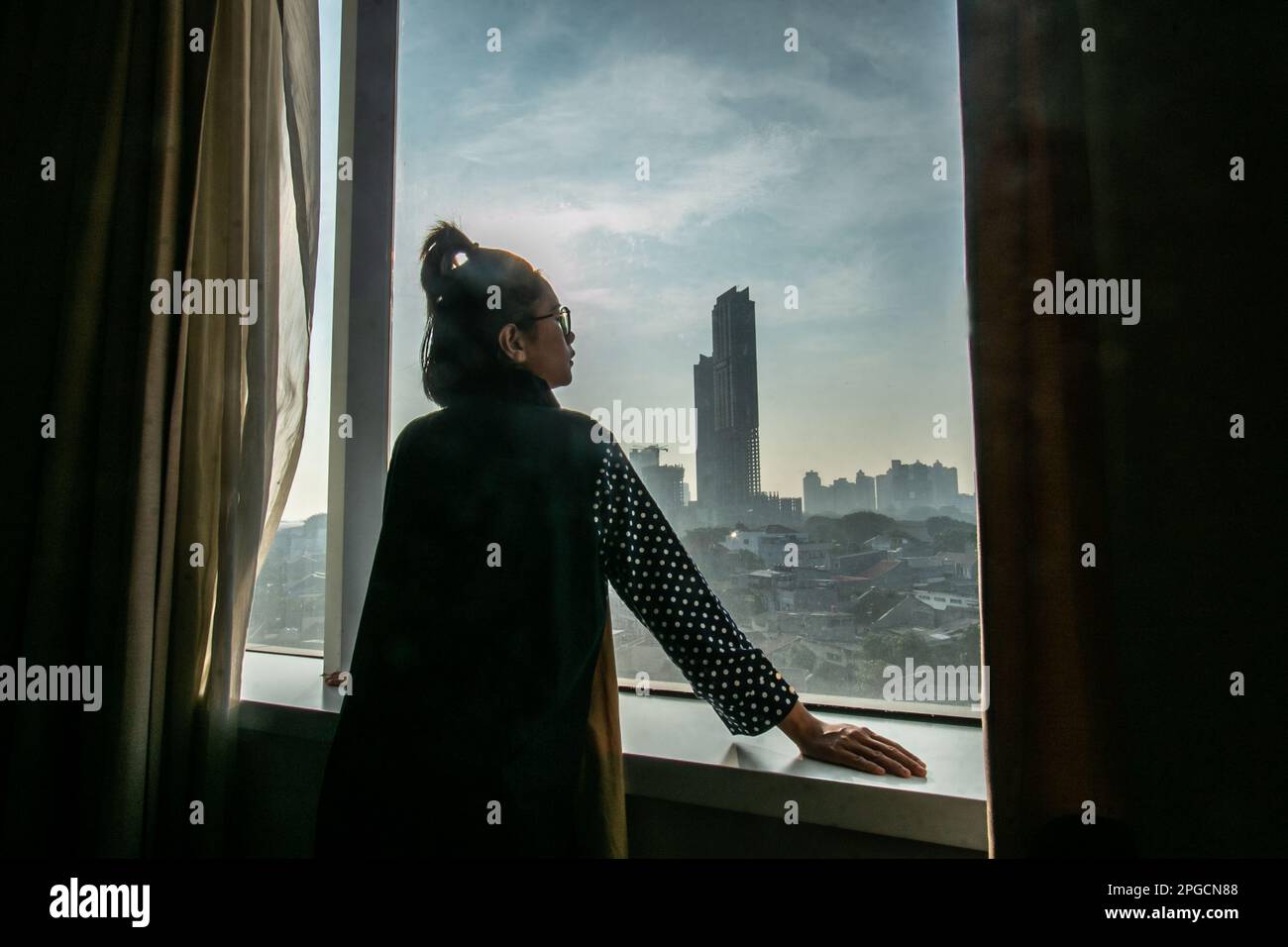 JAKARTA, INDONESIA - March 21, 2023: A woman with her cell phone inside a hotel room in the ...