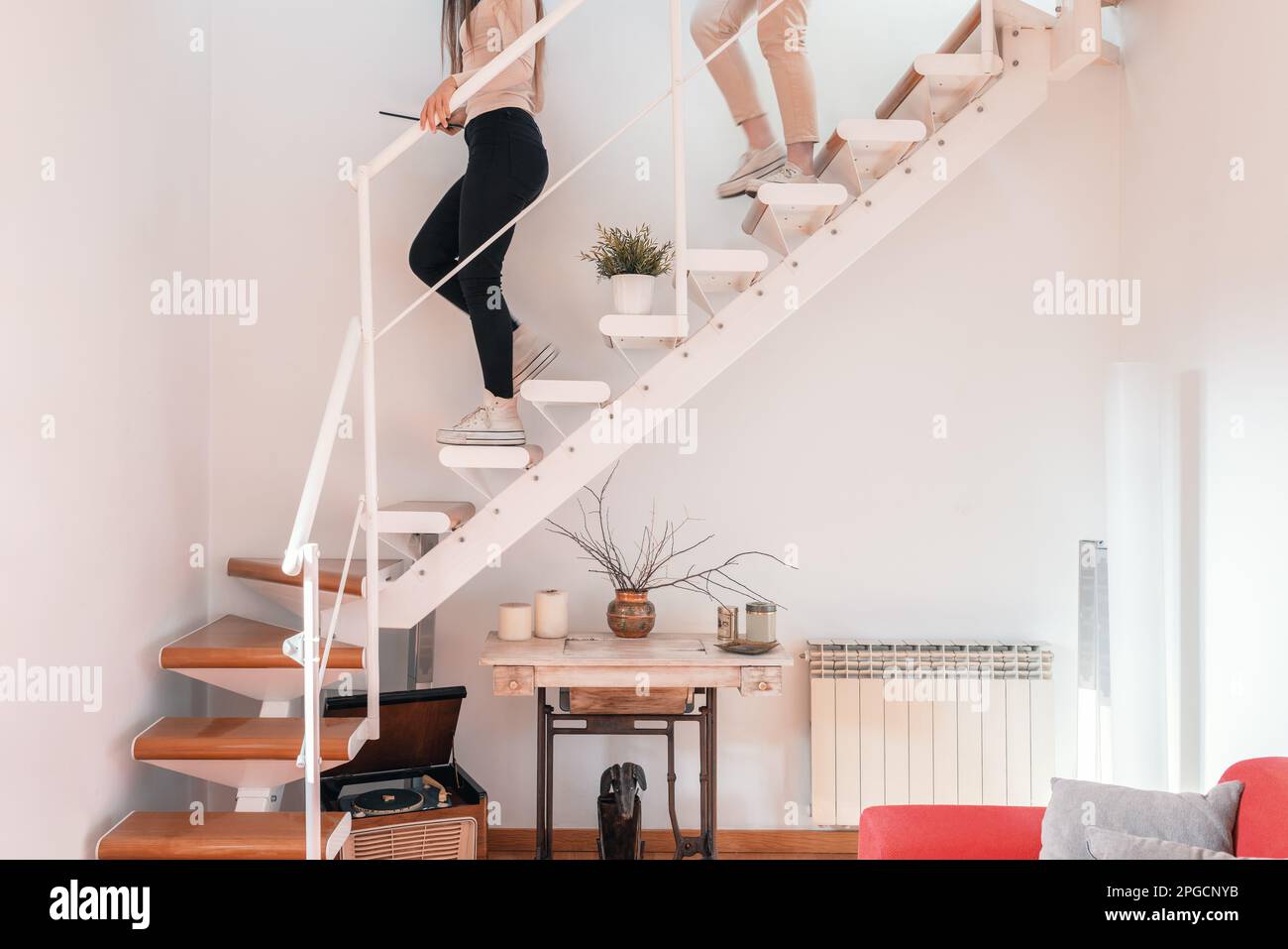 Smiling female with tablet and unrecognizable lady climbing down steps ...