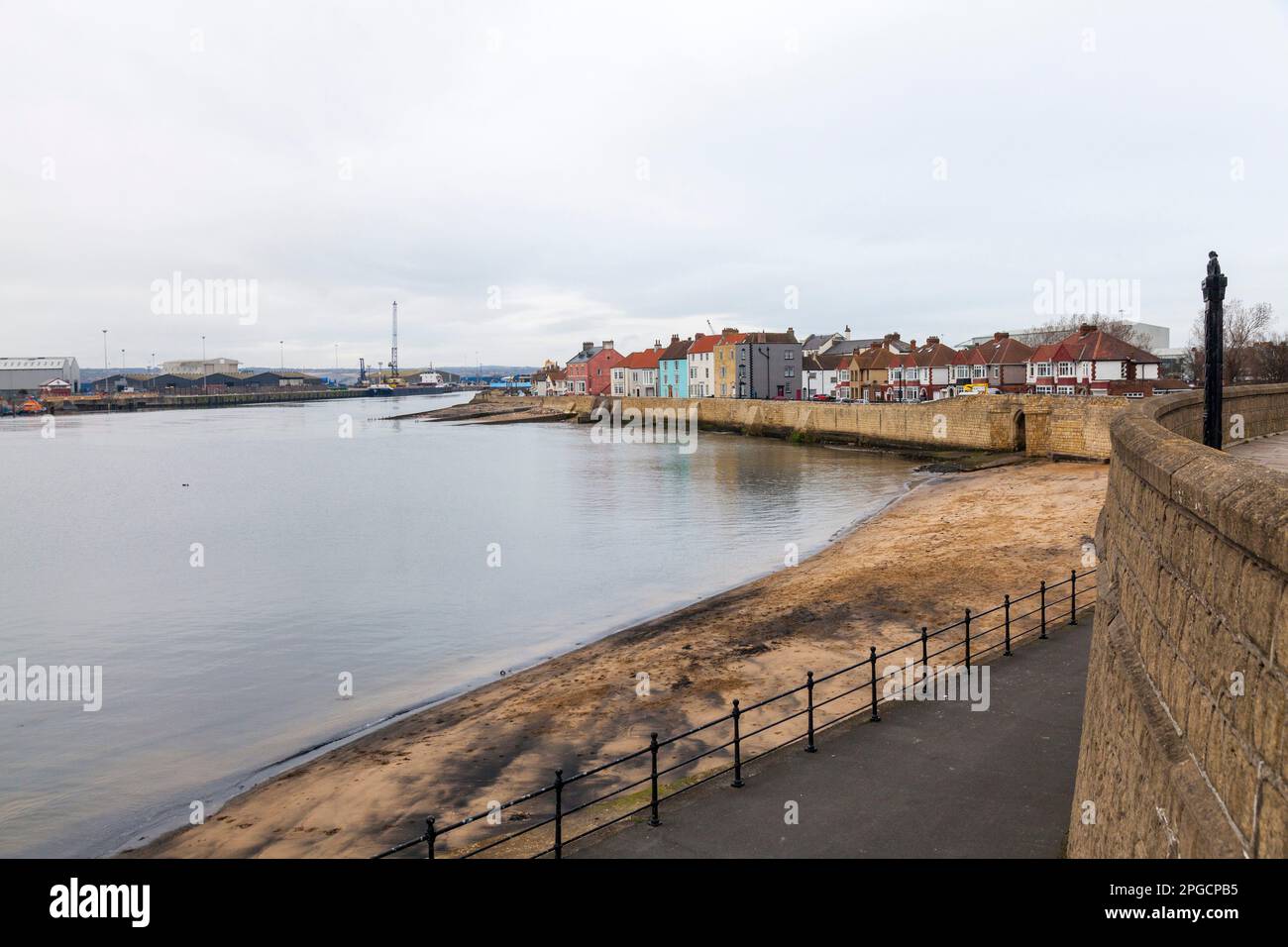 The beach,sea walls and houses with the cranes in the background at the ...