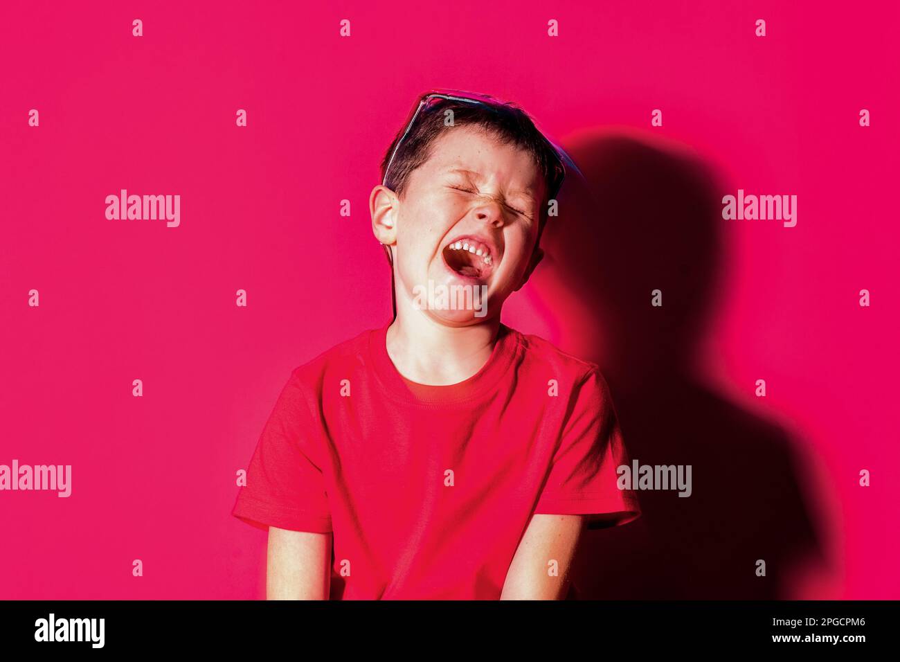 Upset boy in red t shirt screaming and crying with opened mouth and ...