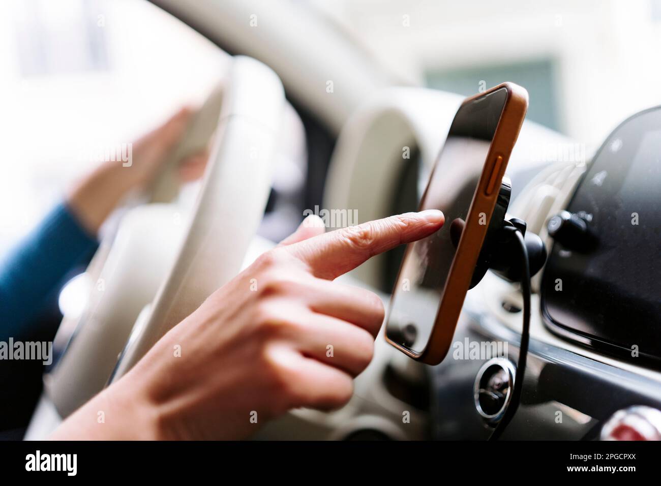 Crop anonymous female driver using navigator in smartphone while ...