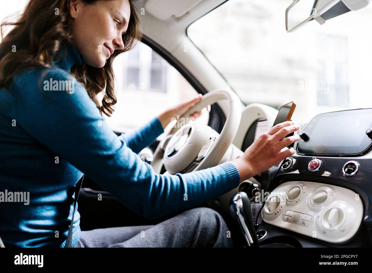 Side view of female driver using navigator in smartphone while driving ...