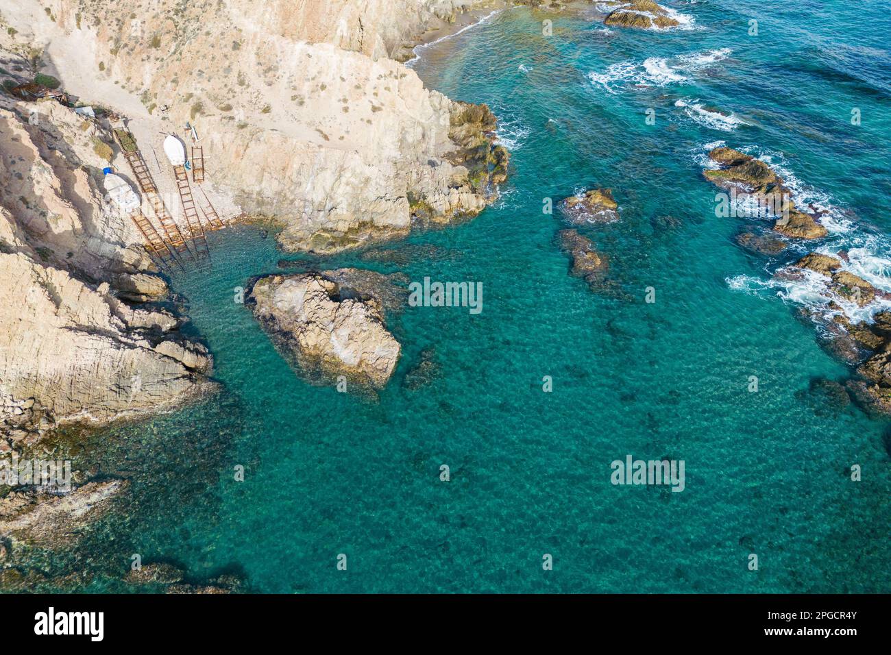 From above drone view of rough rocky cliffs in turquoise rippling ocean ...