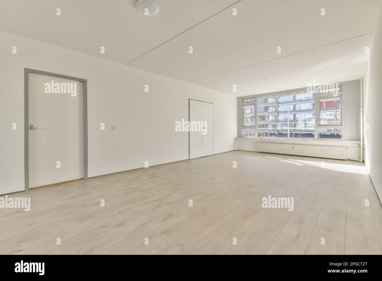 Light spacious room with wooden floor and radiator under window in ...