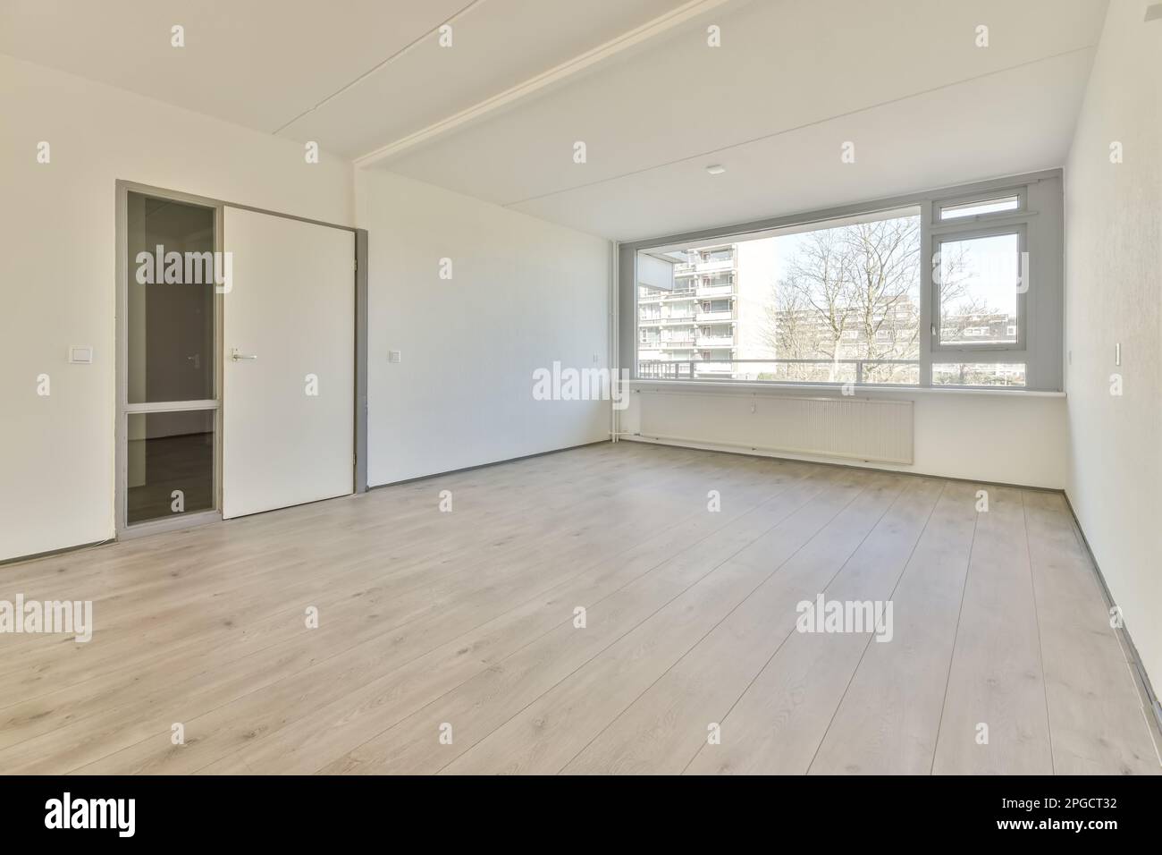 Light spacious room with wooden floor and radiator under window in ...