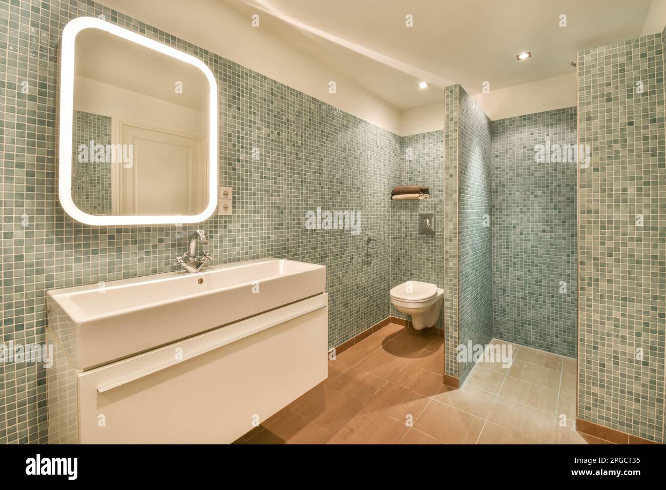 Contemporary restroom interior with mirror placed above sink and toilet ...