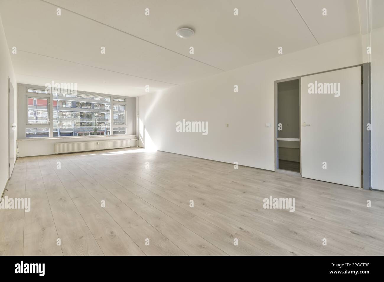 Light spacious room with wooden floor and radiator under window in ...