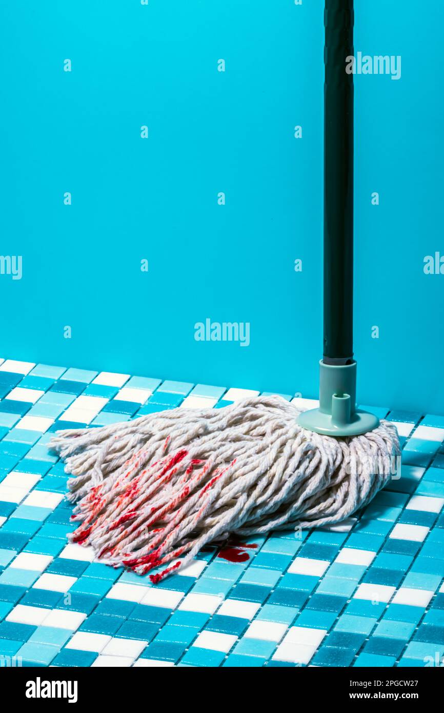 Wash mop with blood spots on blue and white mosaic tile placed against ...