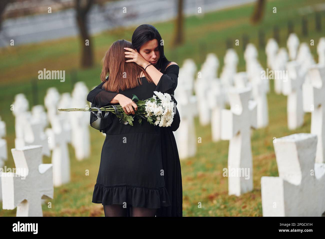 Embracing each other and crying. Two young women in black clothes ...