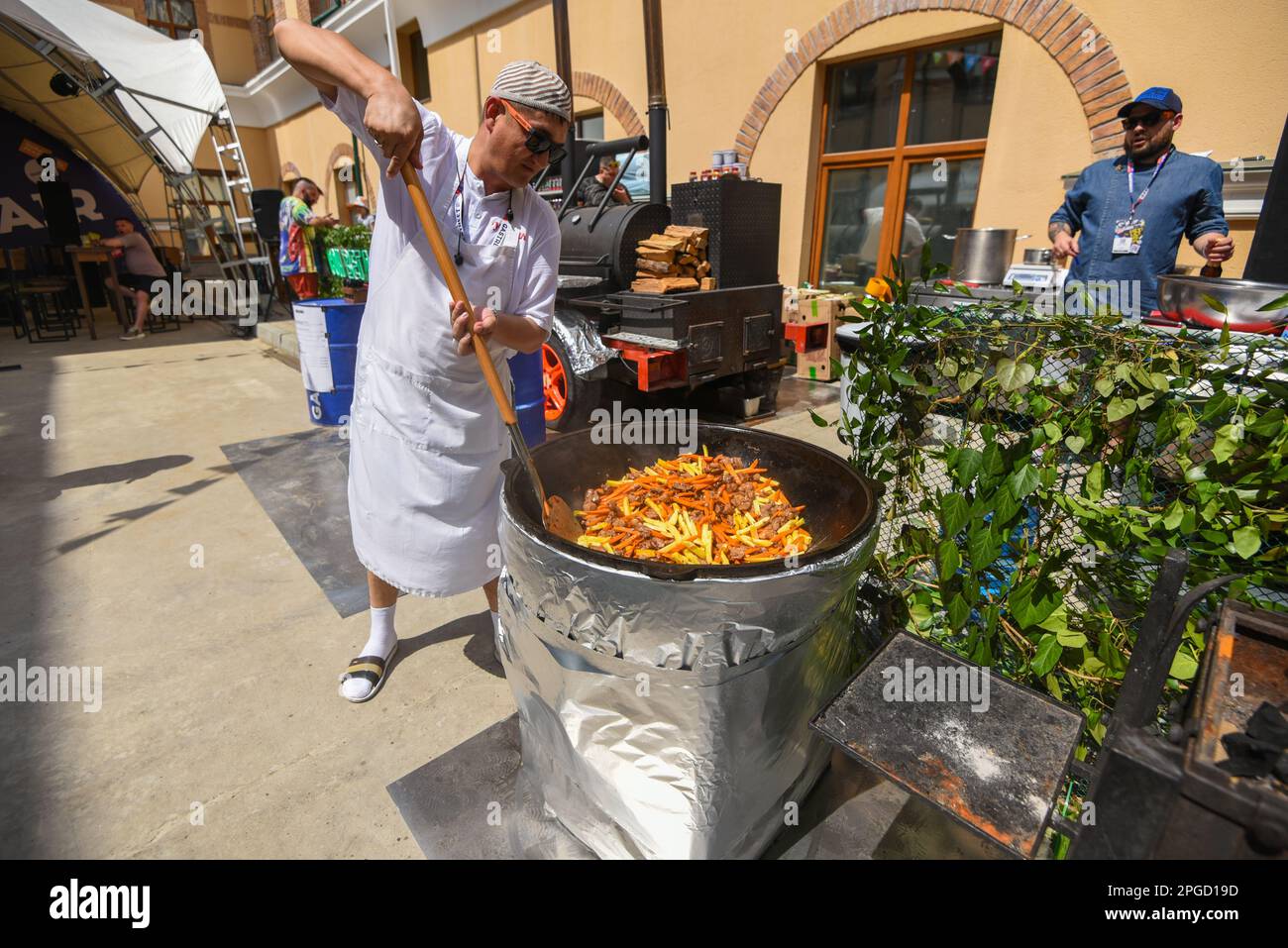 Cook cooks pilaf in a cauldron. Pilaf with vegetables and meat cooked ...