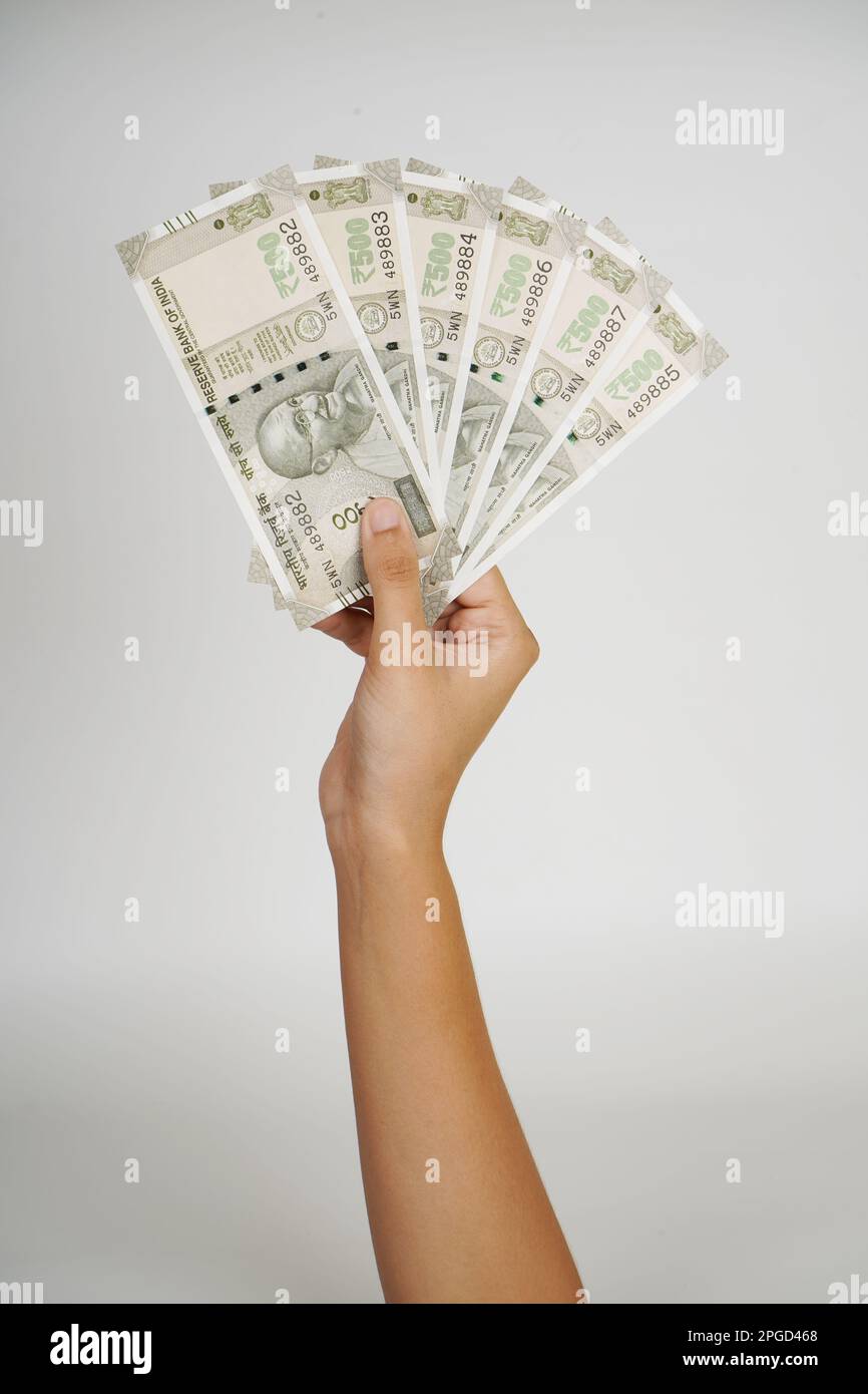 Indian rupee note in hand on grey background Stock Photo - Alamy