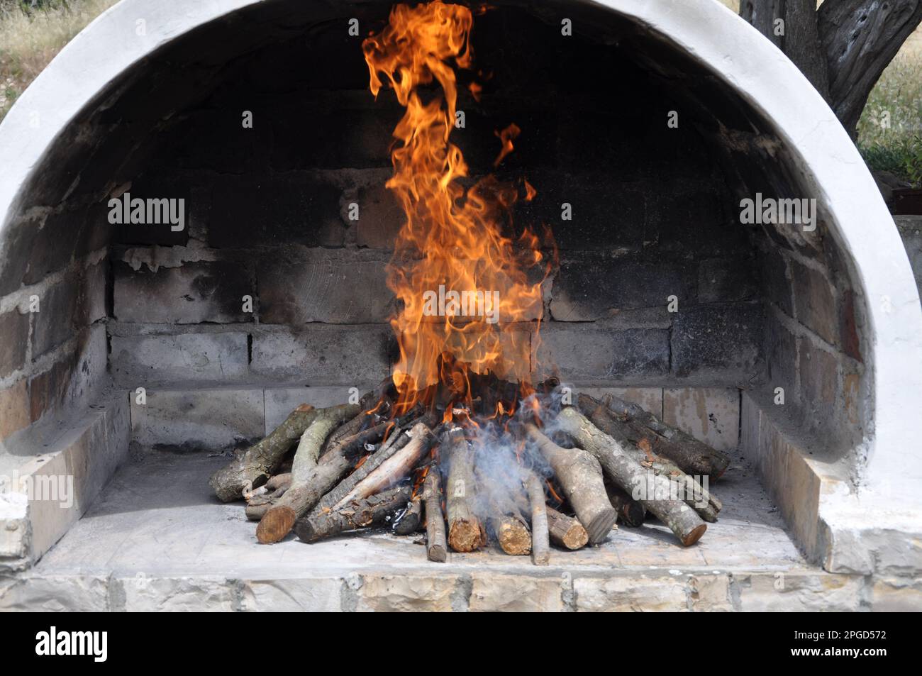 Garden fireplace with a chimney, made of old bricks, with a fire inside ...