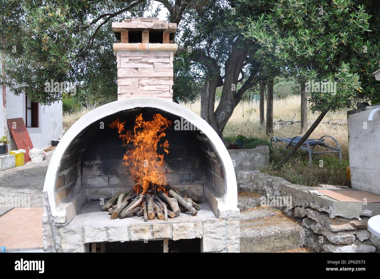 Garden fireplace with a chimney, made of old bricks, with a fire inside ...