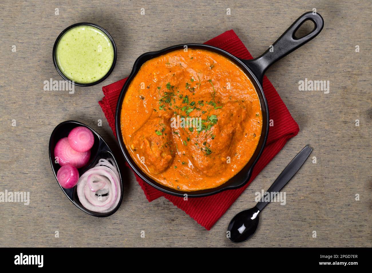 Top view of butter chicken served with pickled onion and mint chutney ...