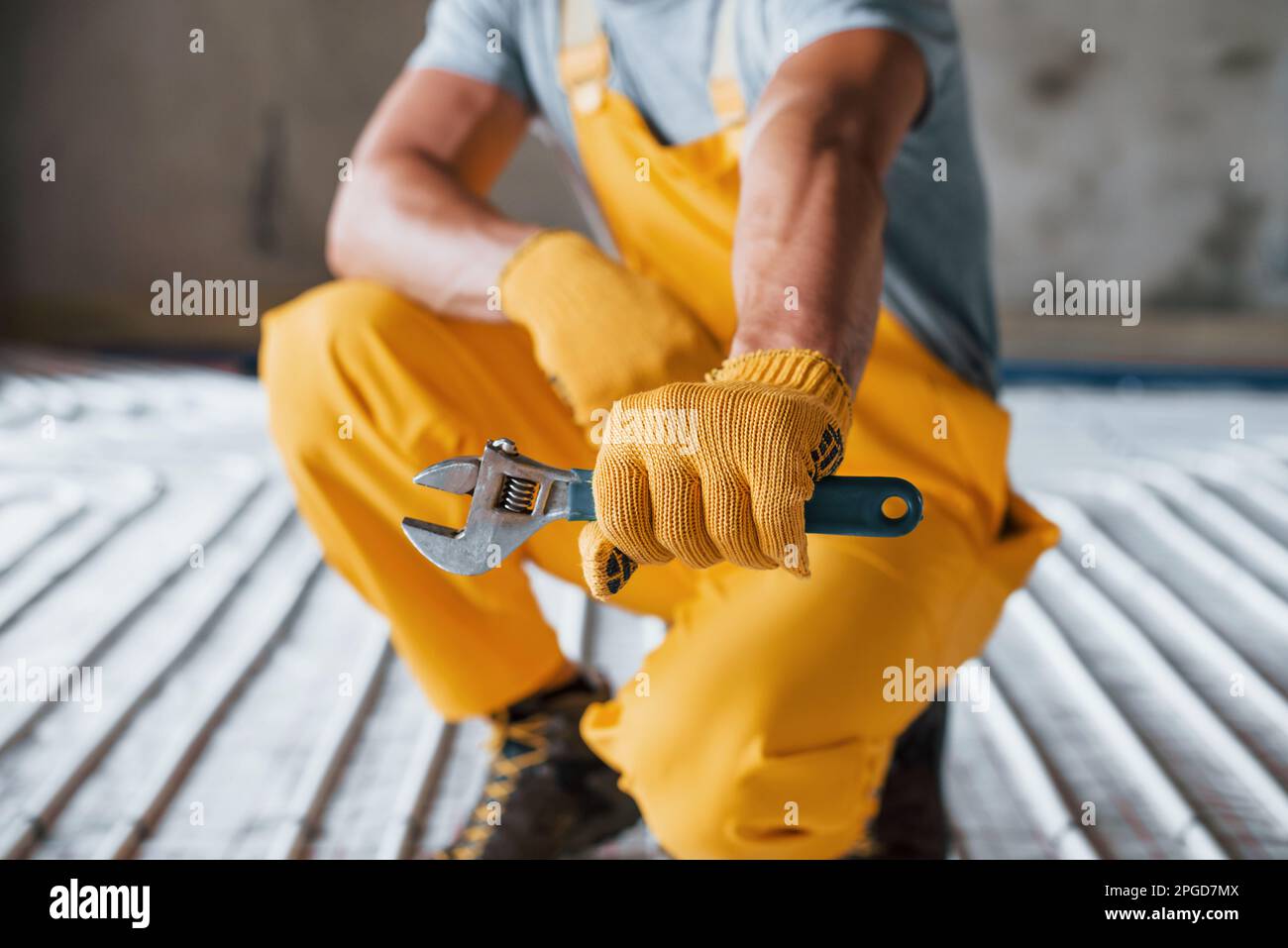 Holds wrench in hand. Worker in yellow colored uniform installing ...