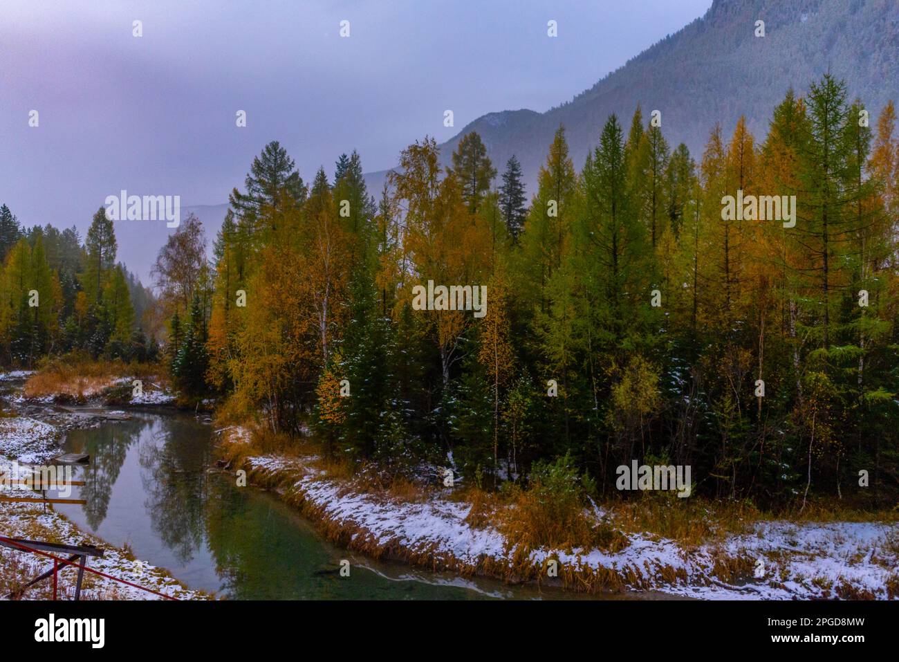 Stairs lead to a small clear river at night with fog in the snow of ...