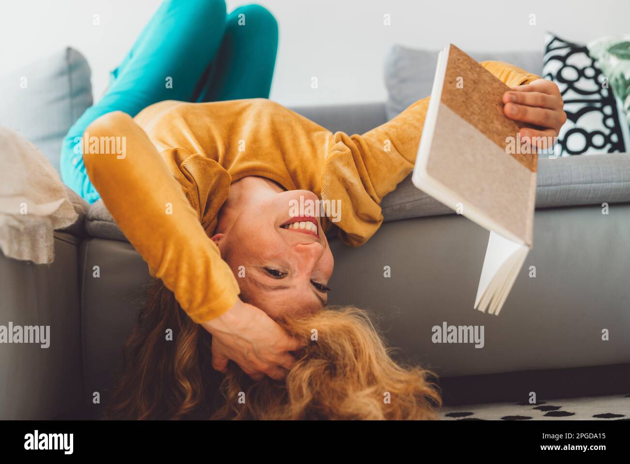 Trying to read upside down - Playful blonde curly woman reading a book ...