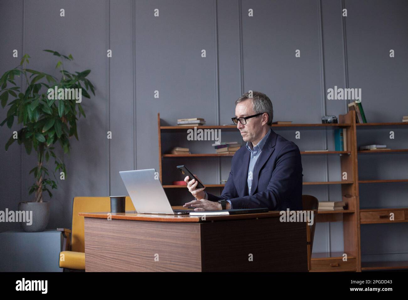 Elderly businessman with grey hair in glasses working on laptop while ...