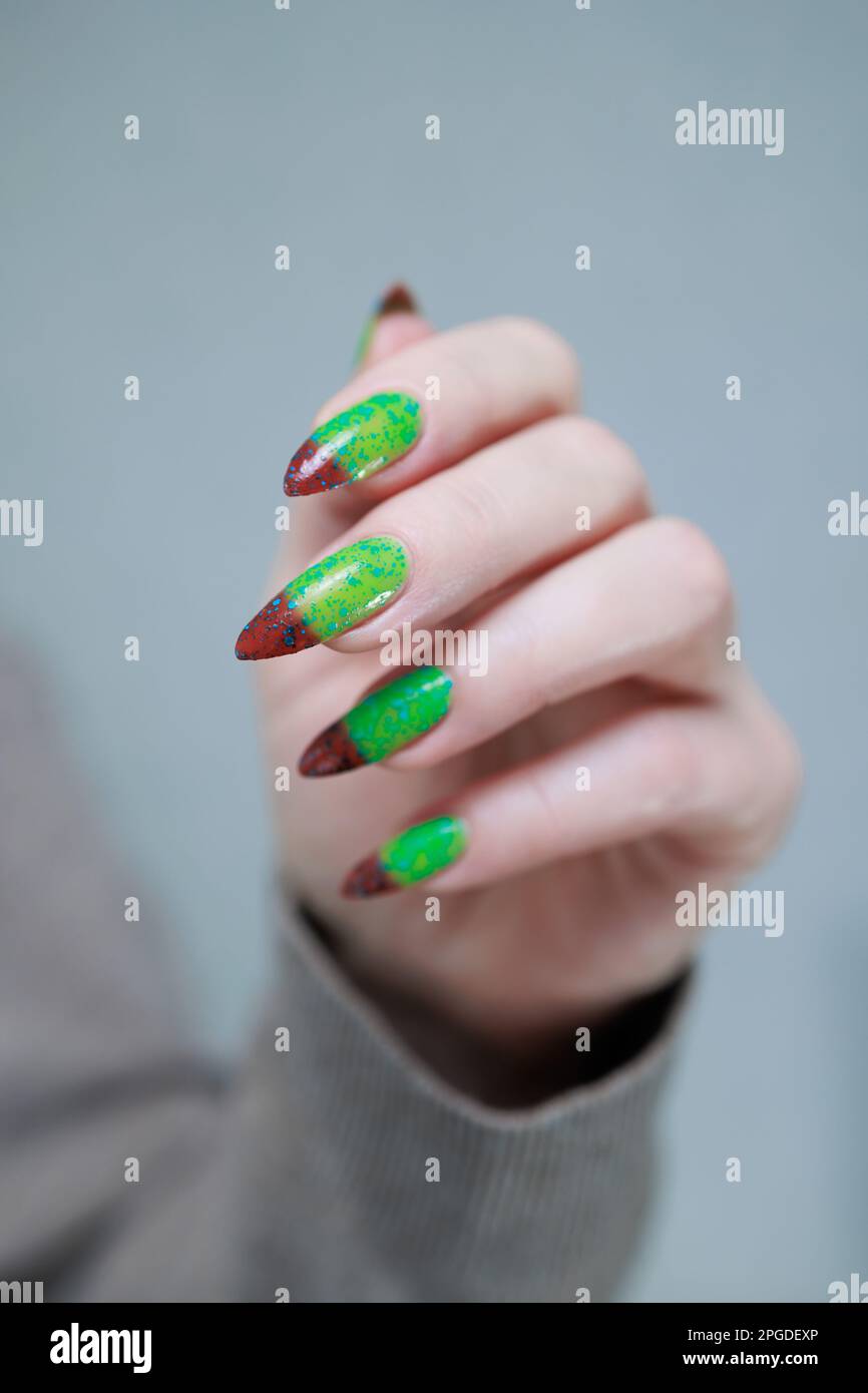 Female hands with long nails and green and brown thermo manicure Stock ...