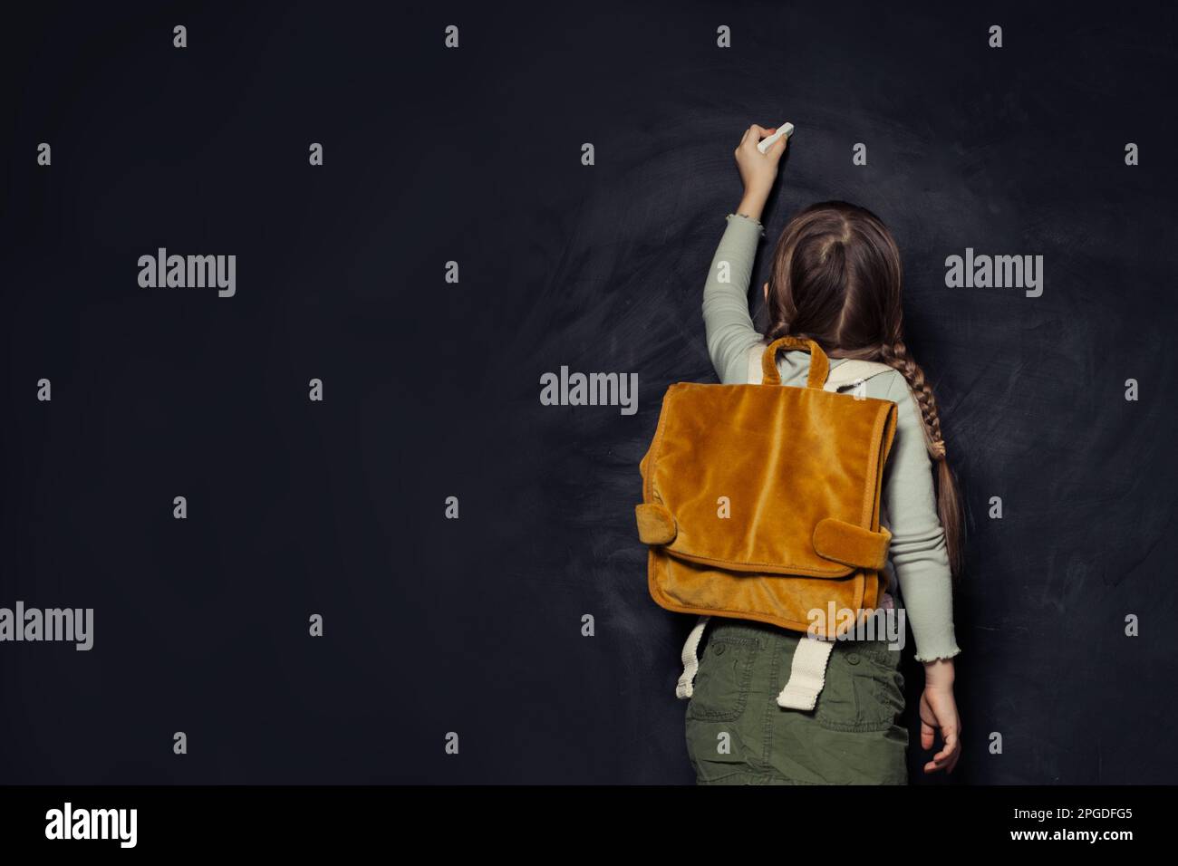 Child girl with backpack standing with her back and writing on school ...