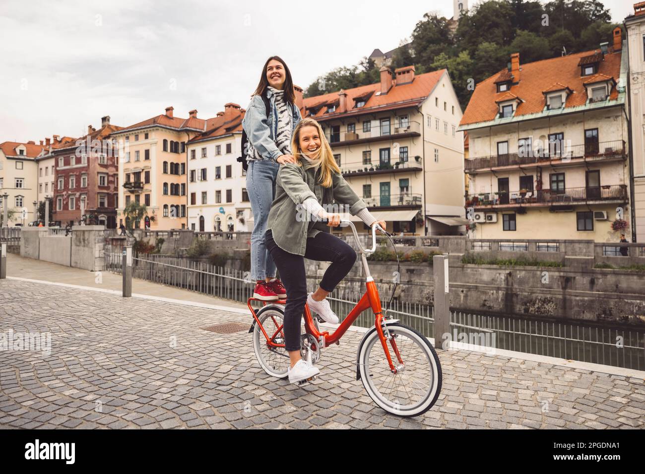 Couple of best friends riding a bike on the city streets, one of the ...