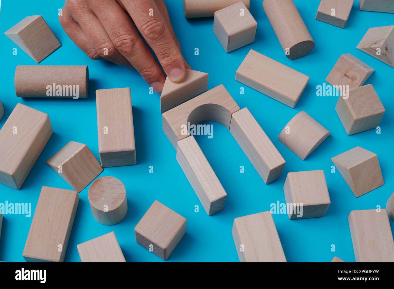 man forming a house with some wooden building blocks on a blue ...