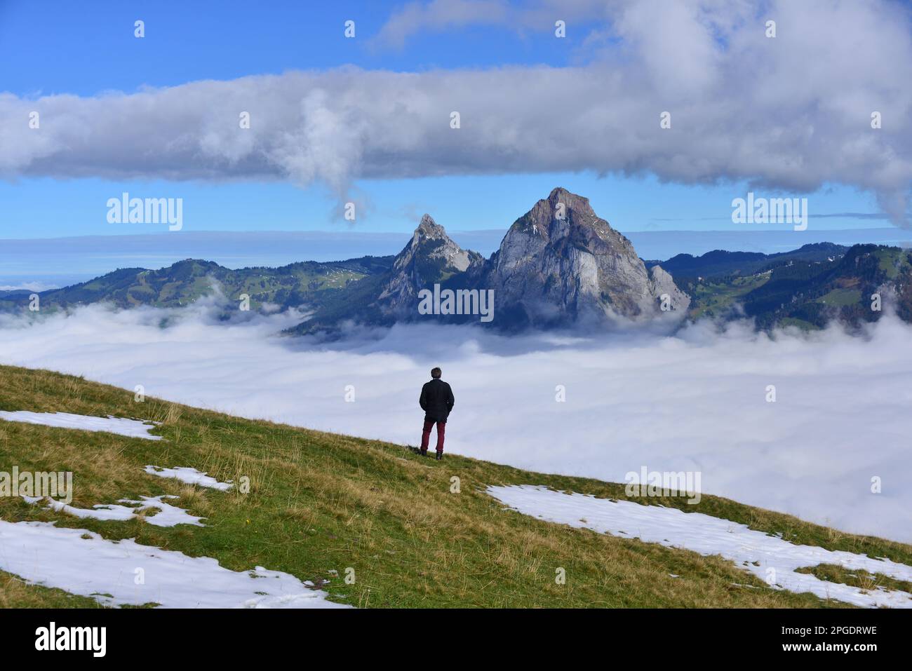 Rear view of a man standing on a hill looking at mountain landscape ...