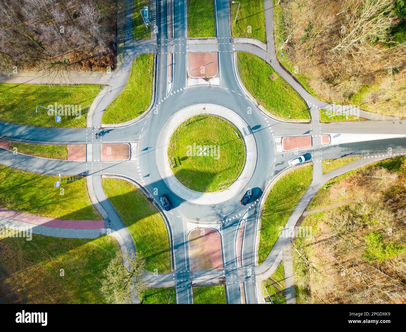 An aerial view of a city street intersection with lush trees in full ...