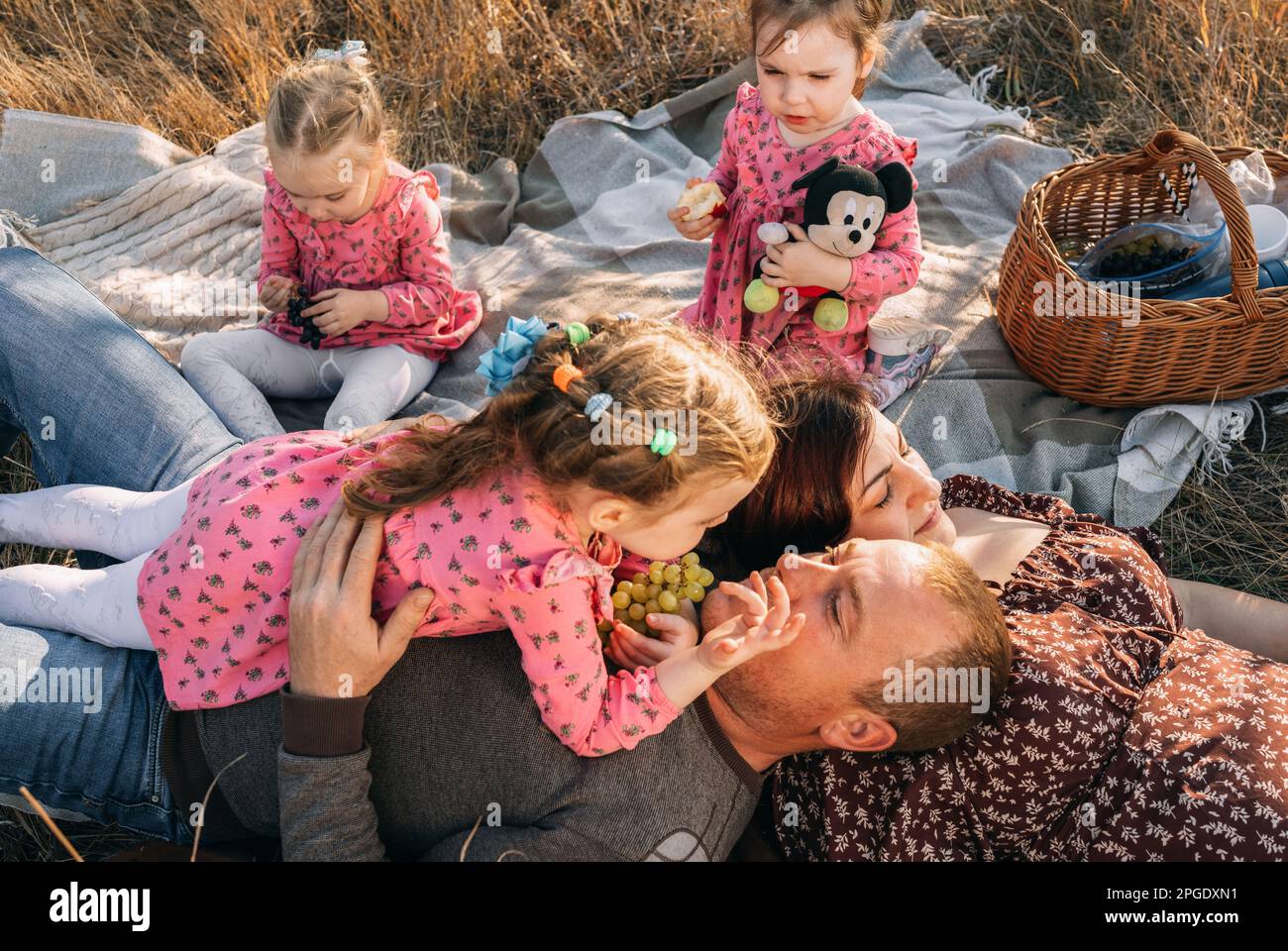 happy family with triplet girls is lying in park, relaxing in the ...