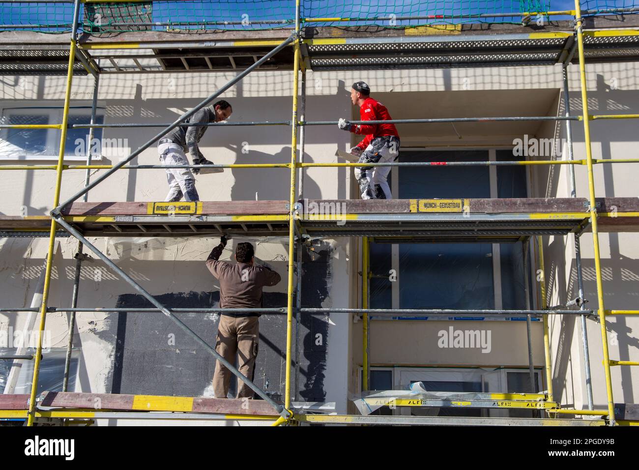 Plasterers plaster the facade of a new building Stock Photo - Alamy