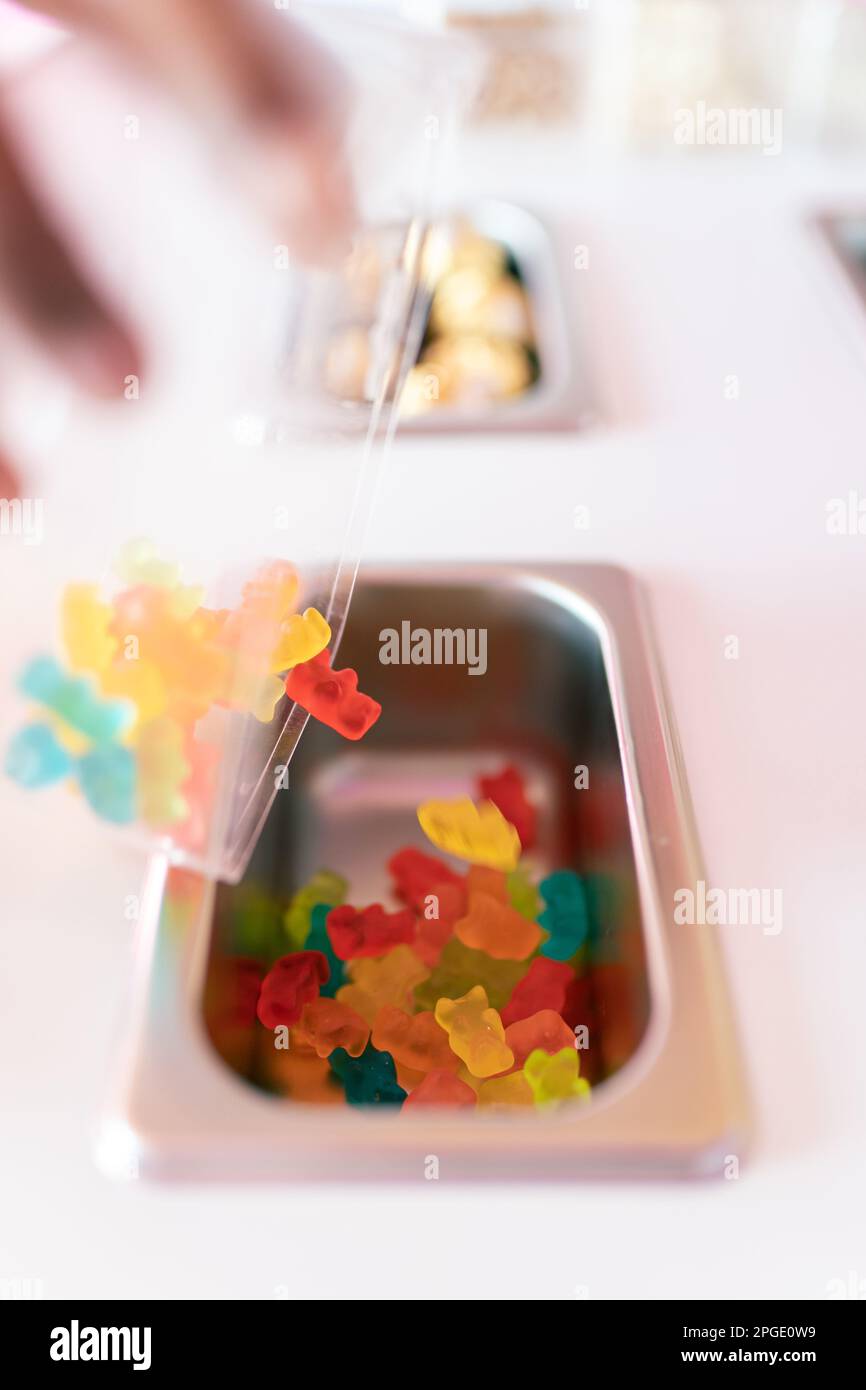 An ice-cream parlor worker is dropping some teddy bear gummies into the ...