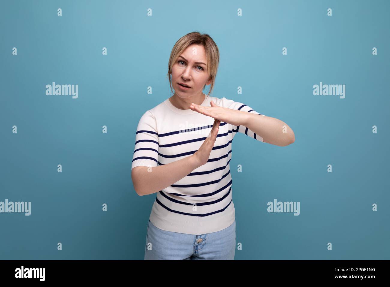 concentrated blond girl shows hand gesture letter t on blue background ...