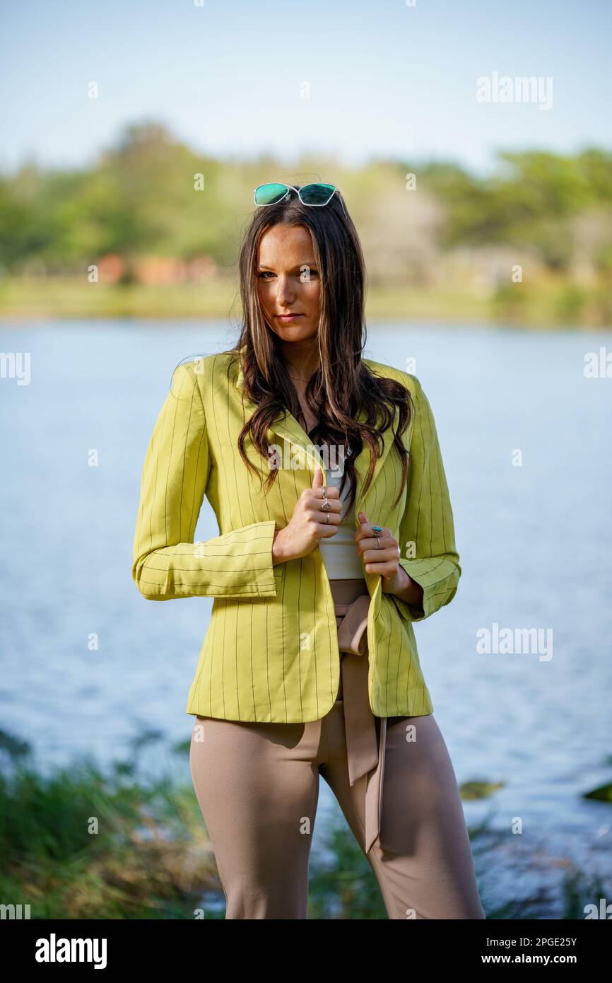 Beautiful young female model posing in a green jacket in a nature seen ...