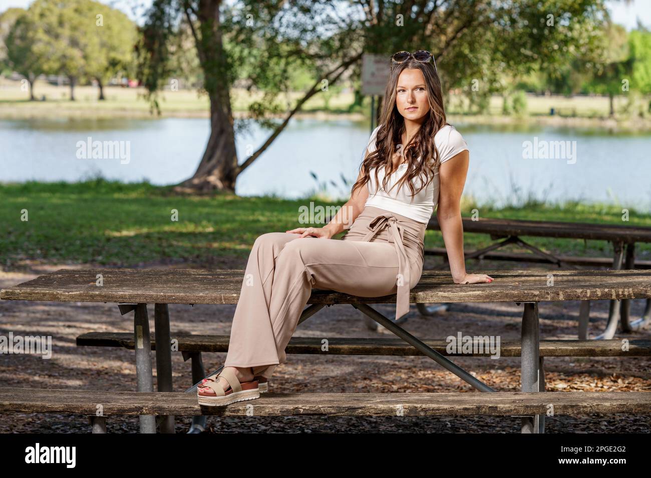 Photo Of A Young Fashion Model Sitting On A Park Bench Glancing Away