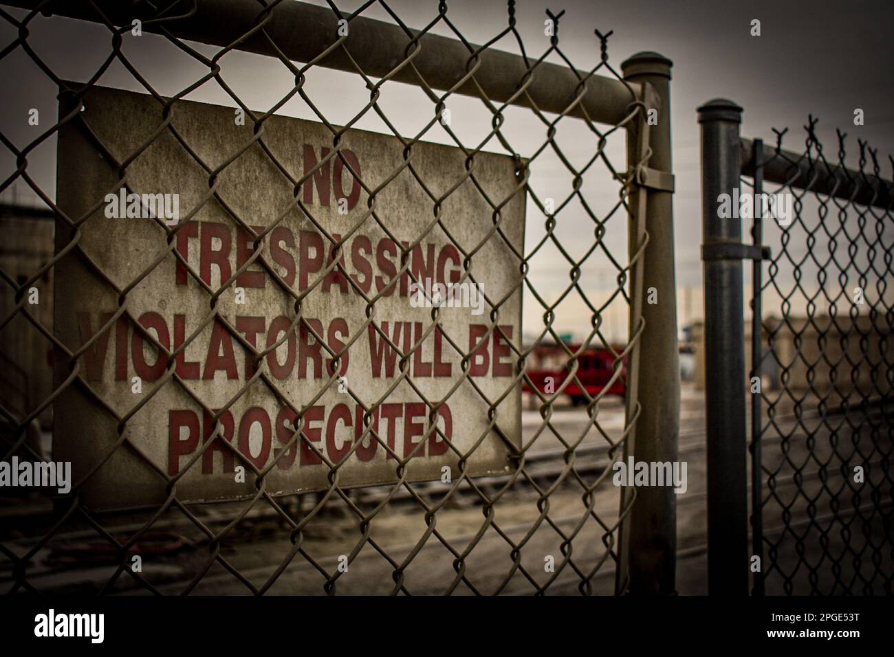 A metal fence with a sign reading "No Trespassing" in bold red ...