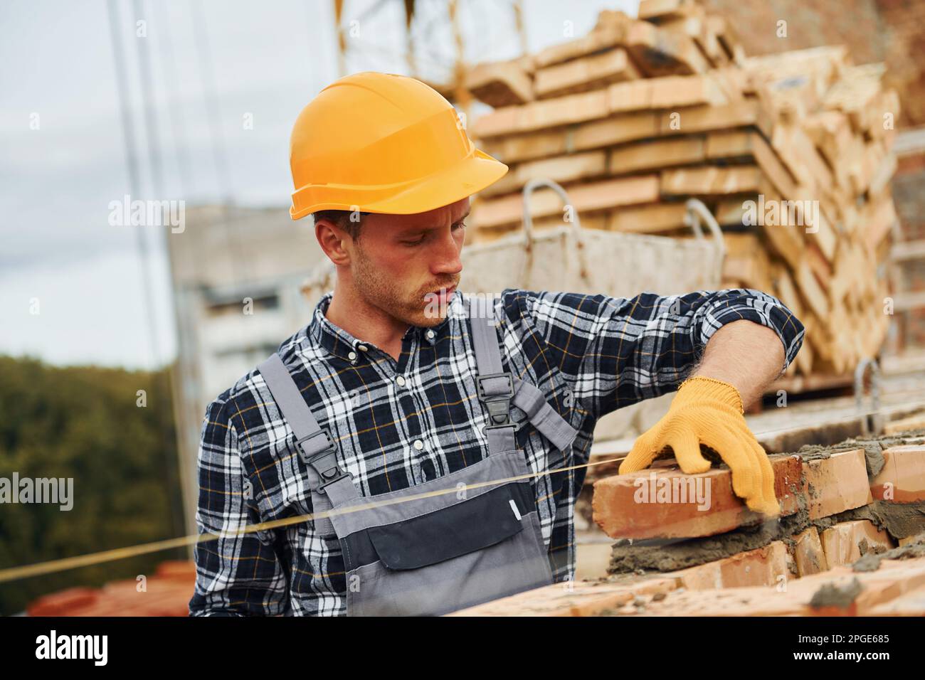 Laying bricks. Construction worker in uniform and safety equipment have ...