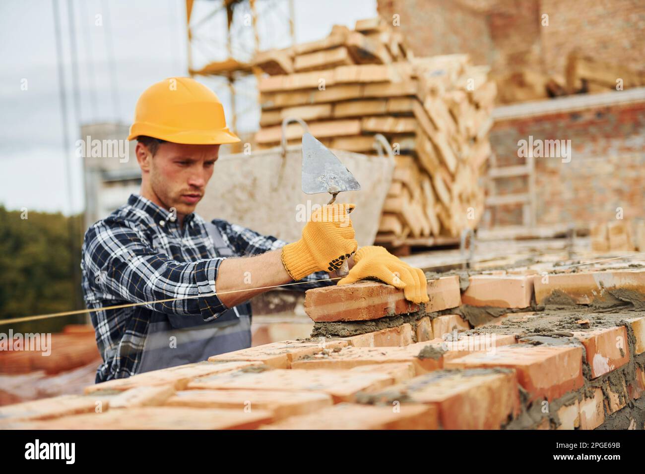 Laying bricks. Construction worker in uniform and safety equipment have ...