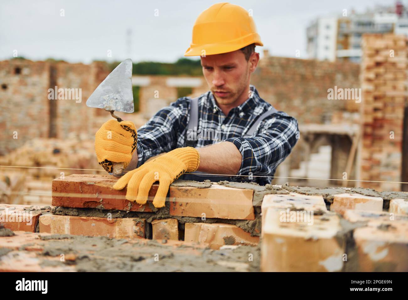 Laying bricks. Construction worker in uniform and safety equipment have ...