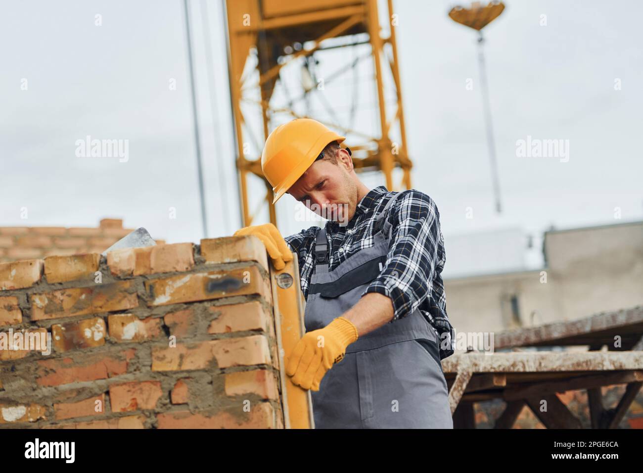 With level measuring tool. Construction worker in uniform and safety ...