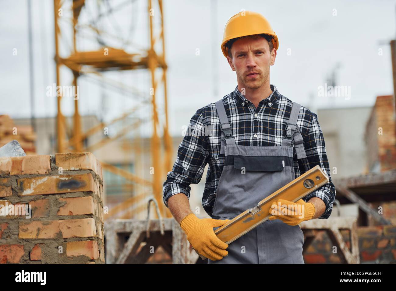 With level measuring tool. Construction worker in uniform and safety ...
