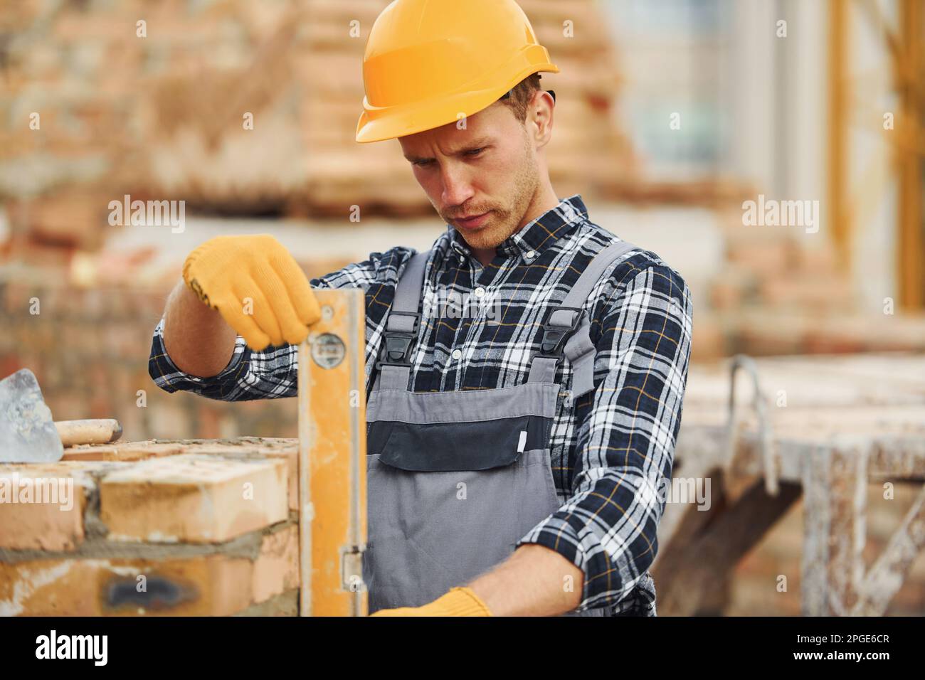 With level measuring tool. Construction worker in uniform and safety ...