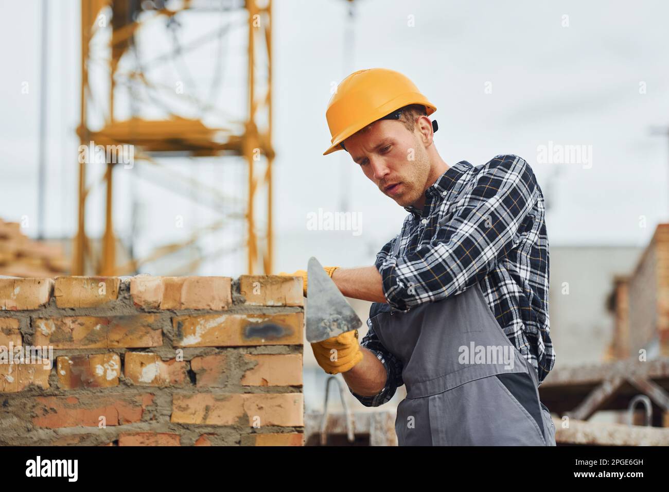 Laying bricks. Construction worker in uniform and safety equipment have ...