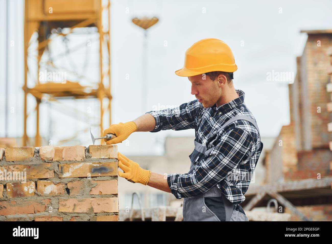 Laying bricks. Construction worker in uniform and safety equipment have ...