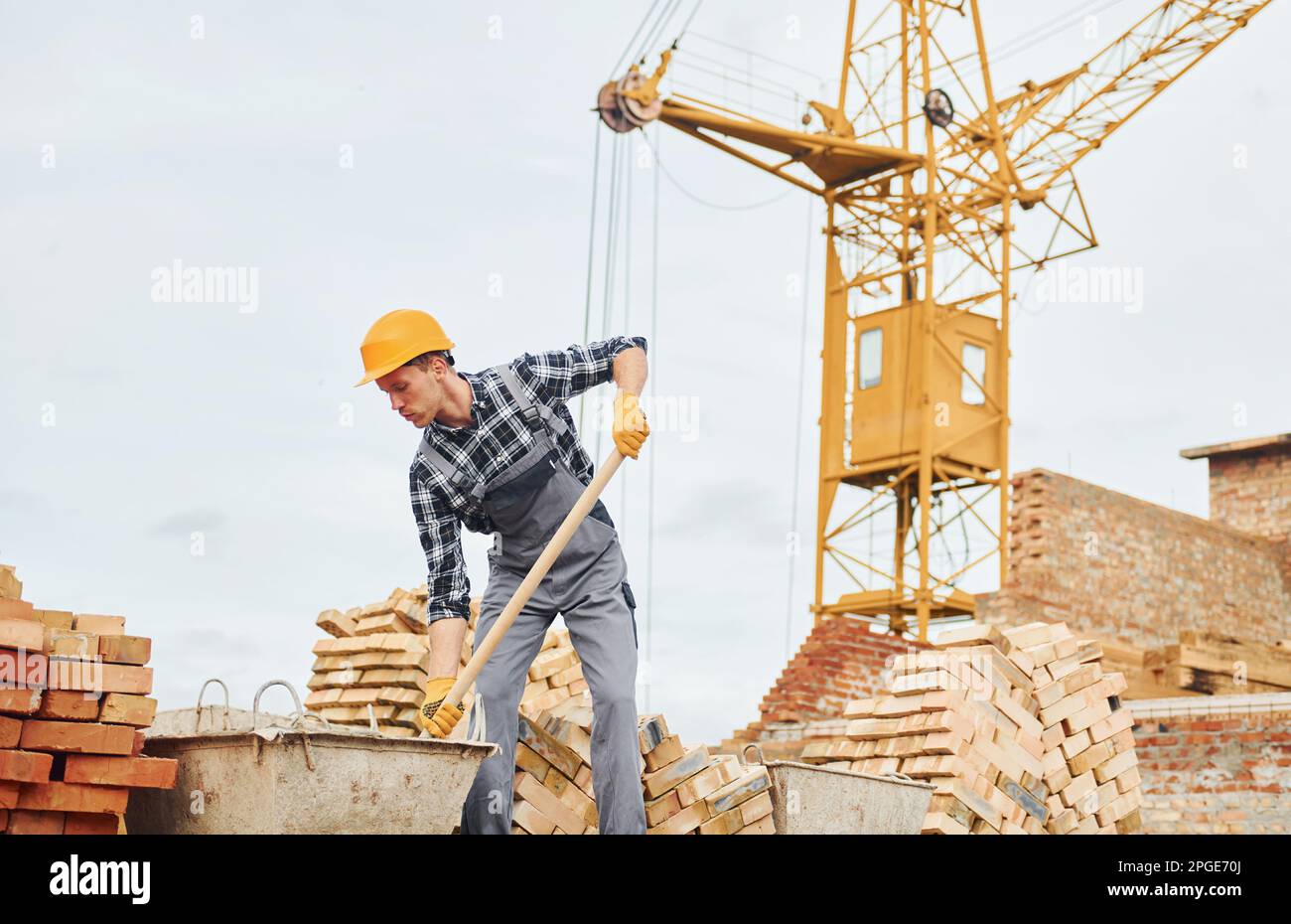 Using shovel with wooden holder. Construction worker in uniform and ...